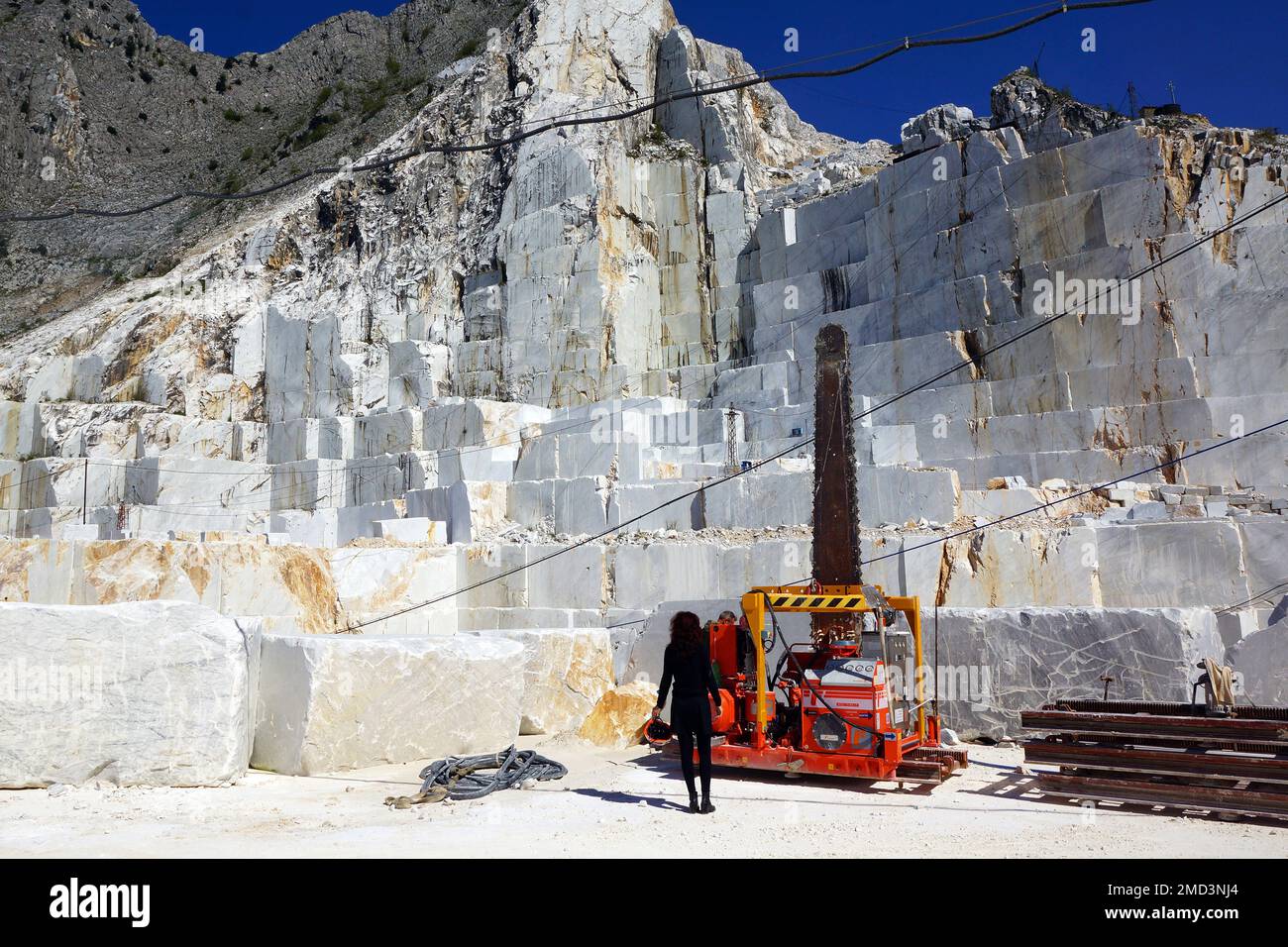 Woman looking at chainsaw cutting machine and marble blocks in the ...