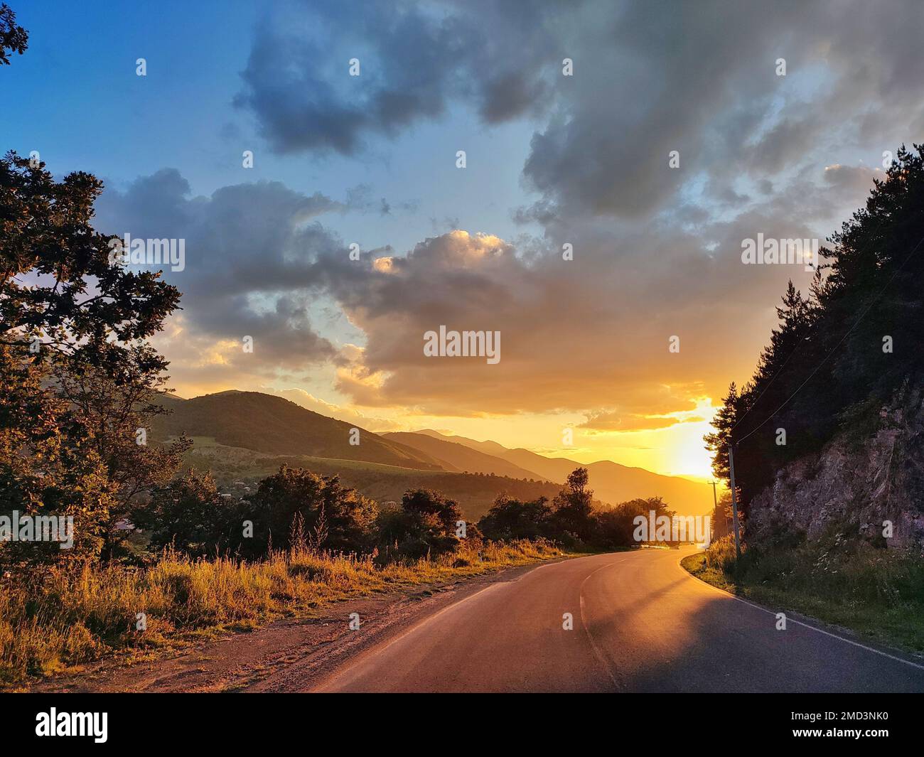 A scenic shot of an asphalt road surrounded by trees and rocks at ...