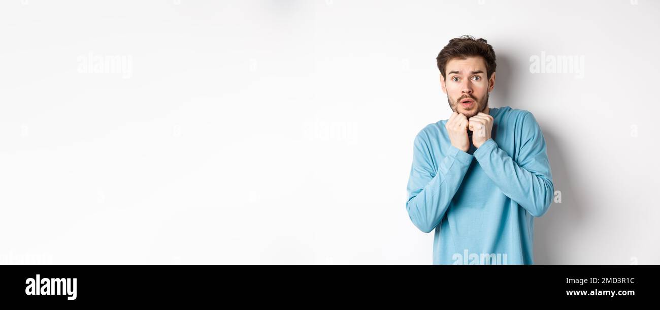 Image of scared young man trembling from fear, holding hands near face ...