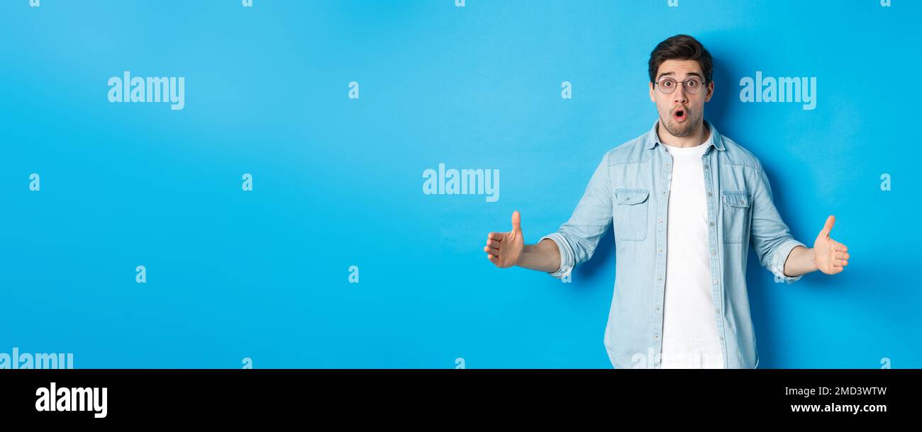 Surprised handsome man holding something big, showing large size with ...