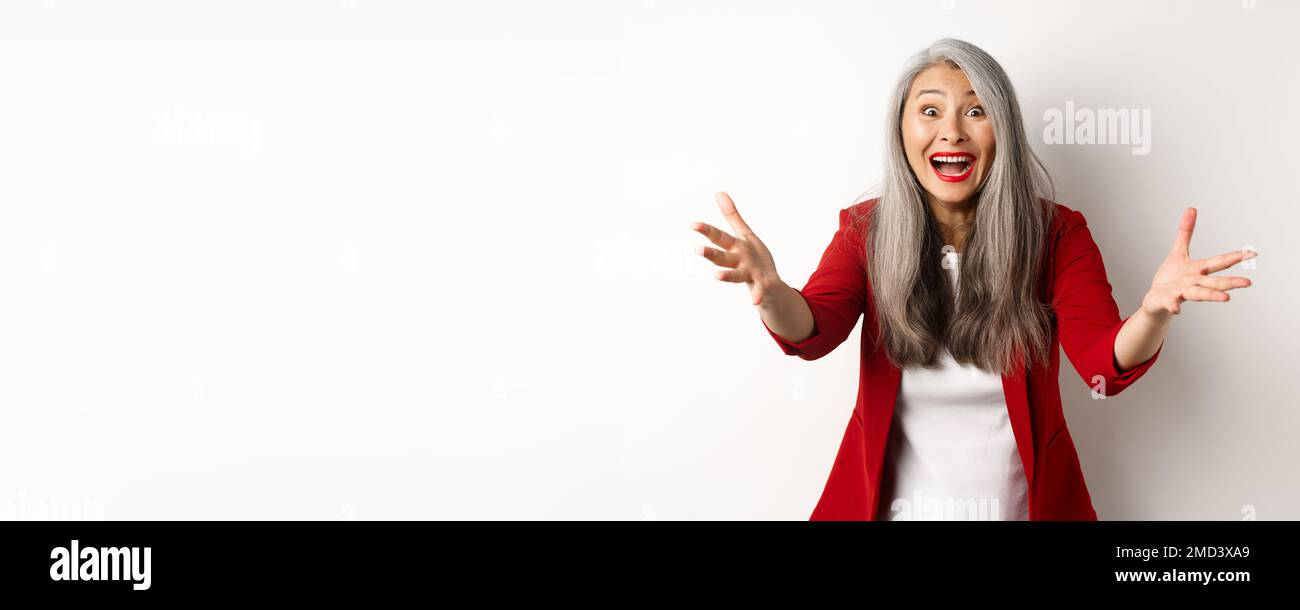 Surprised and friendly asian woman reaching hands forward and smiling ...