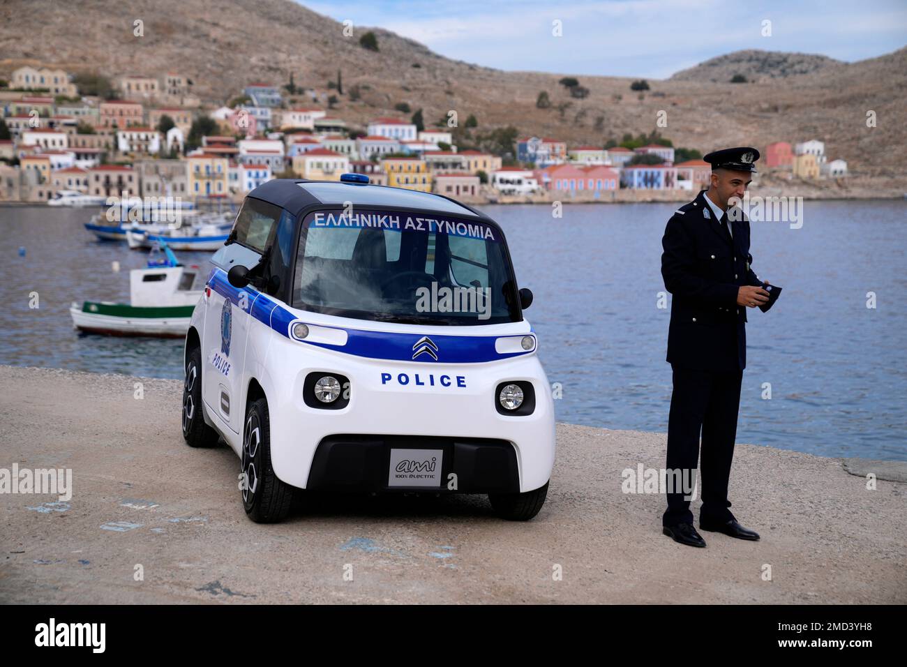 A policeman stands next to an electric police car at the tiny Aegean ...