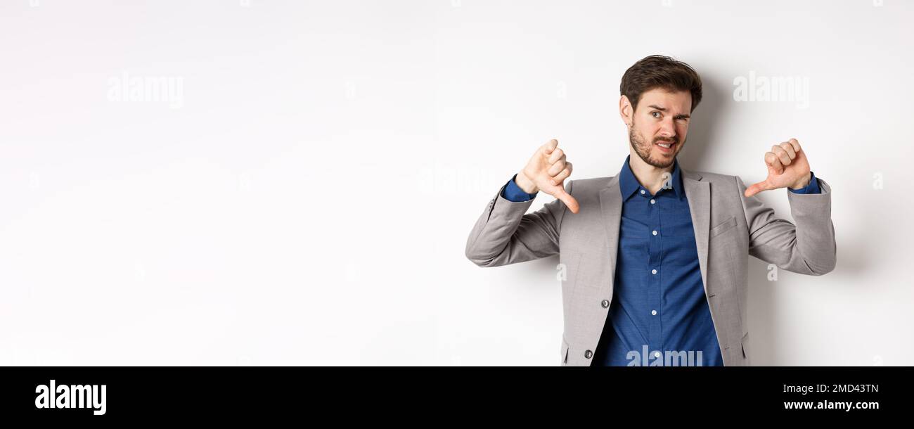 It sucks. Man feeling awkward showing thumbs down and judging something ...