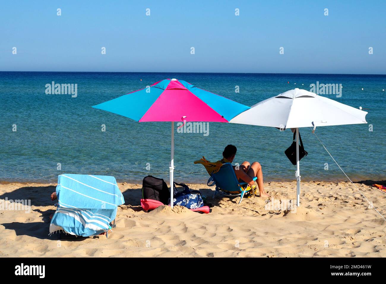 Man relaxing under beach umbrellas on a beach, Sardinia region, Italy ...