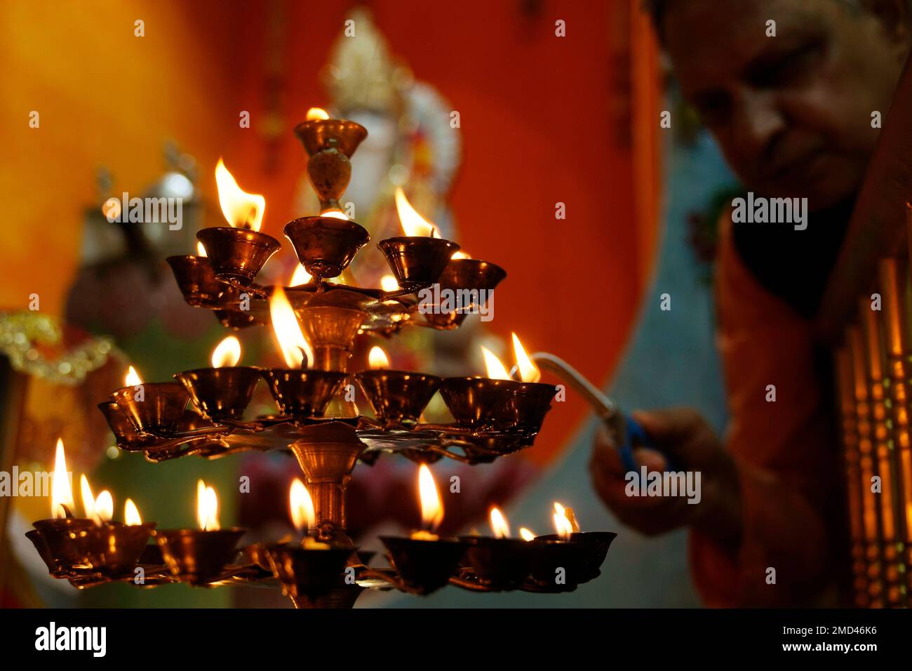 A Hindu devotee lights oil lamps at a temple during Diwali, the ...