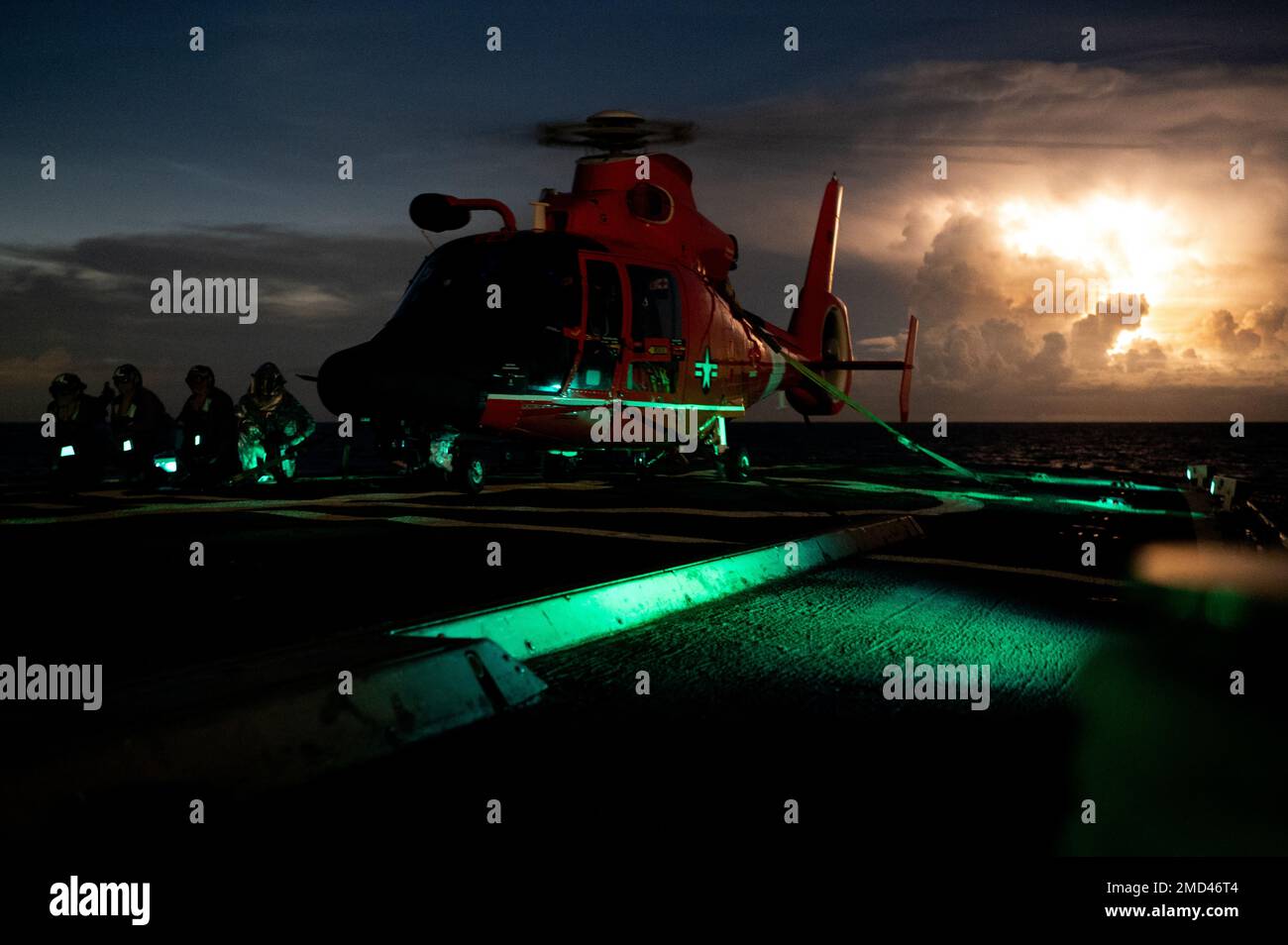 A long exposure photograph shows lightning in the back of crew members ...