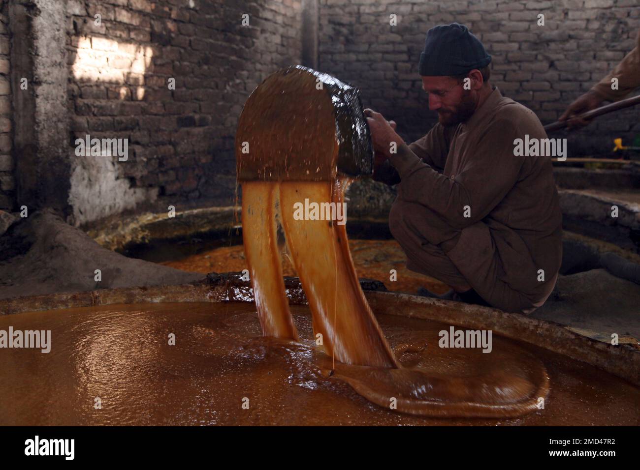 A worker produces sugarcane juice in a traditional juice factory on the ...