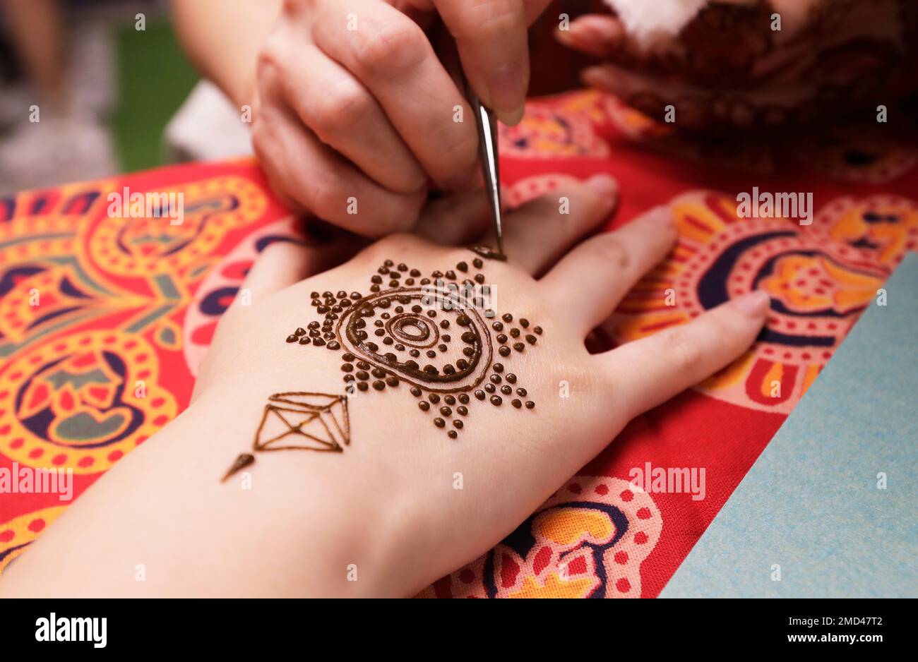 An artist applies henna on the hand of a woman during the Hindu ...