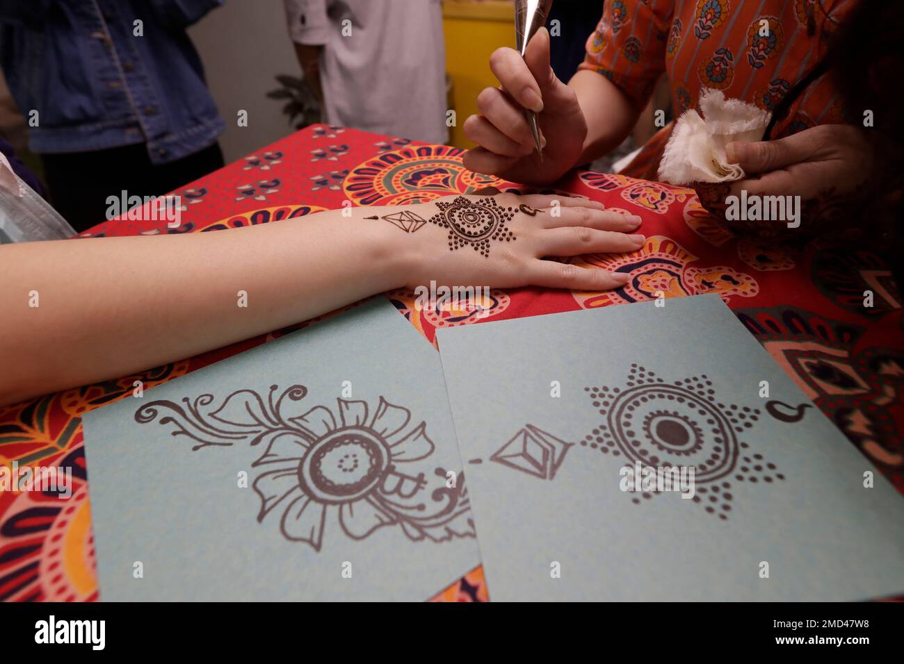 An artist applies henna on a woman's hand during the Hindu festival of ...