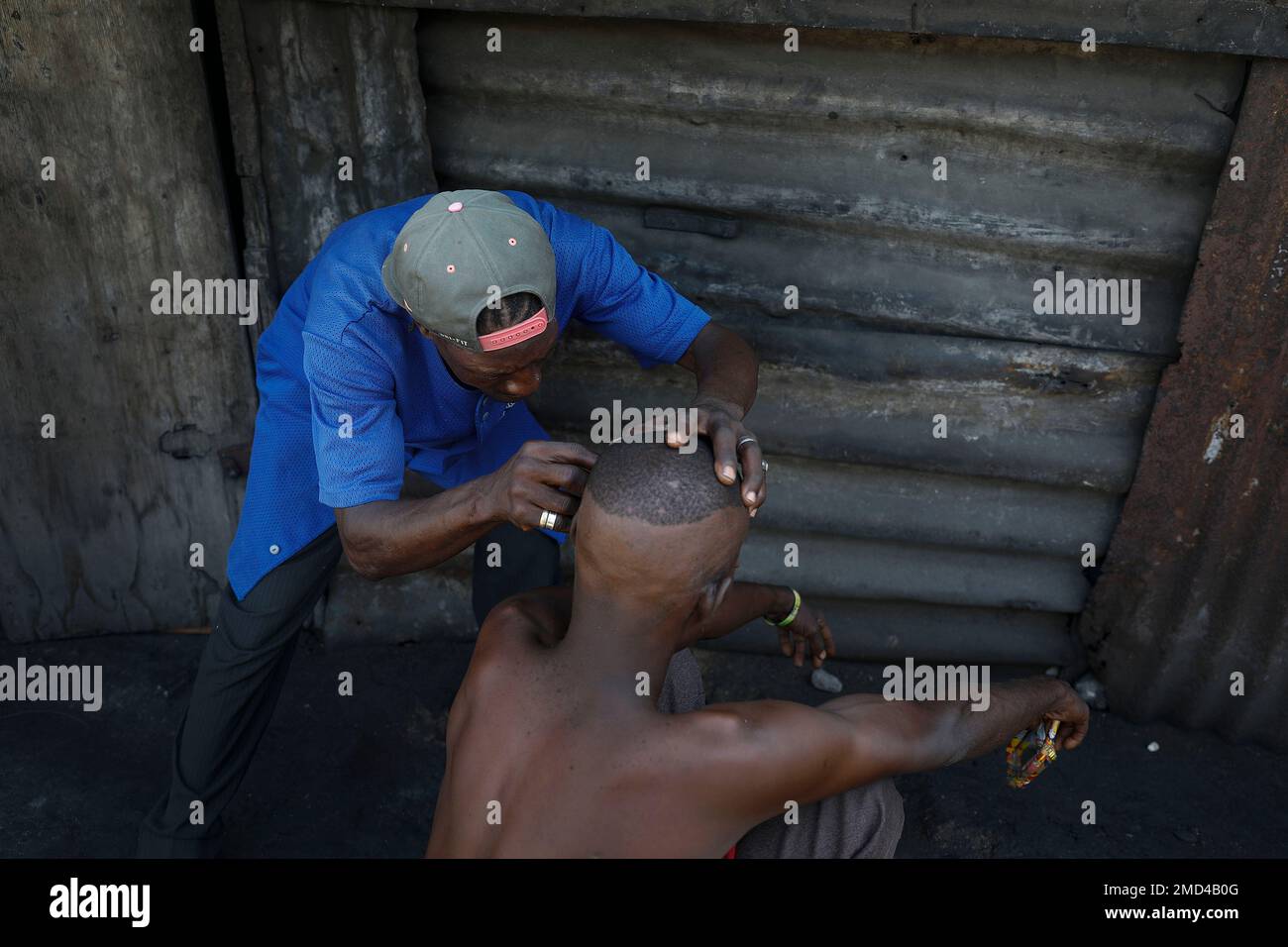 A man cuts another manÂ´s hair at La Saline neighborhood of Port-au ...