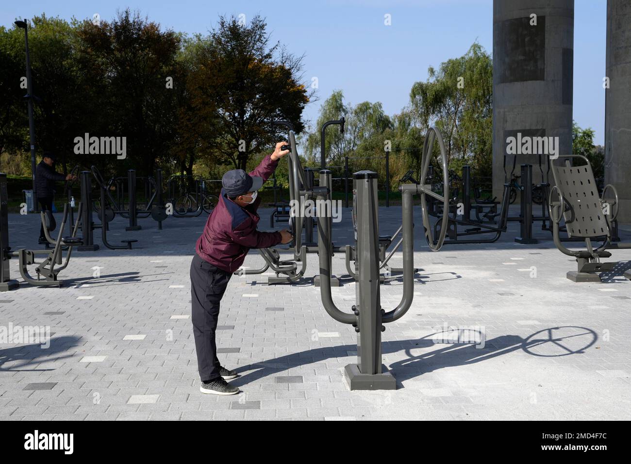 A man wearing a face mask exercises during a lunch break at a park in ...