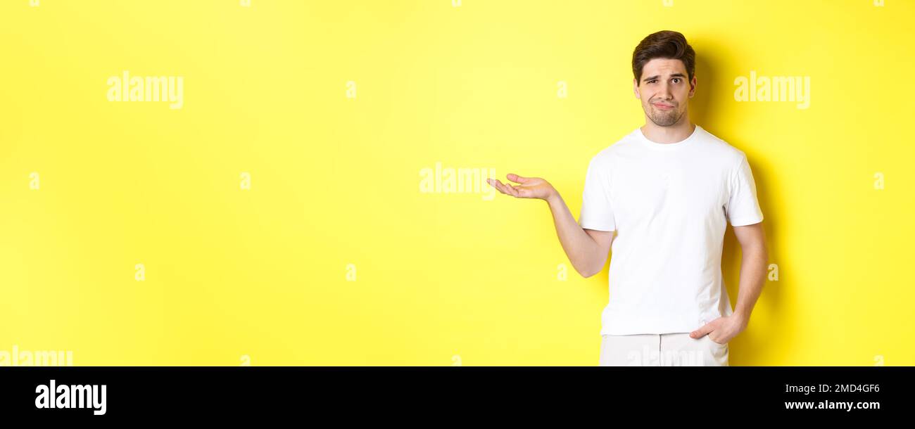 Confused and displeased guy raise hand, grimacing puzzled, standing ...