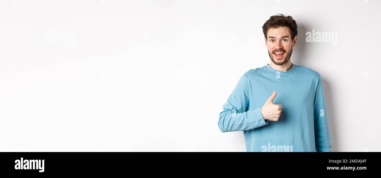Cheerful young man agree and say yes, show thumb up in approval ...