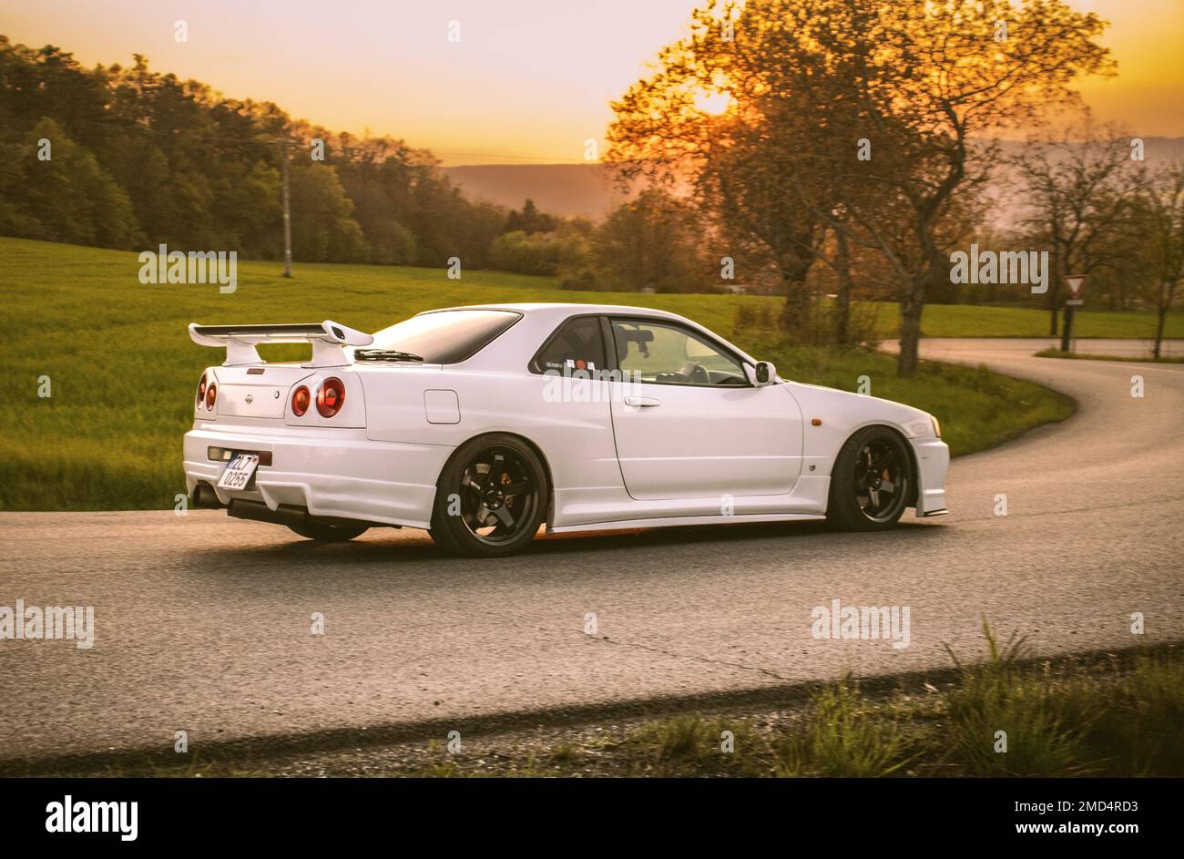 A beautiful white Nissan GTR R34 driving on a road at sunset Stock ...