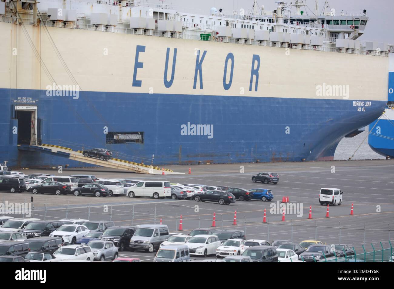 Cars for export are loaded onto a cargo ship at a port in Yokohama ...