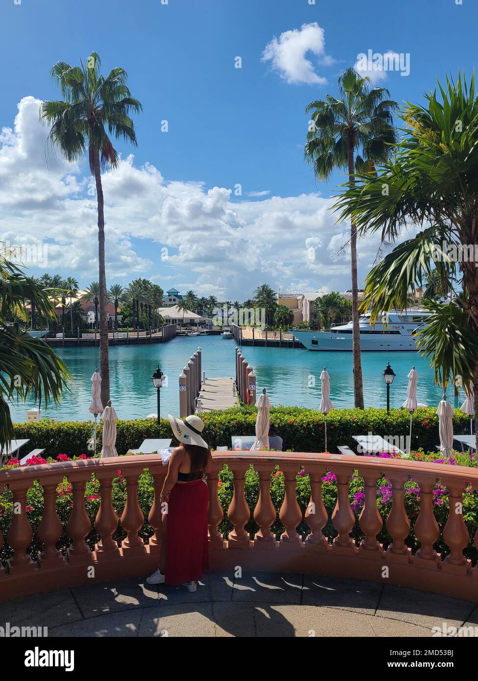 A vertical back view of a girl with hat posing by the beautiful lake ...