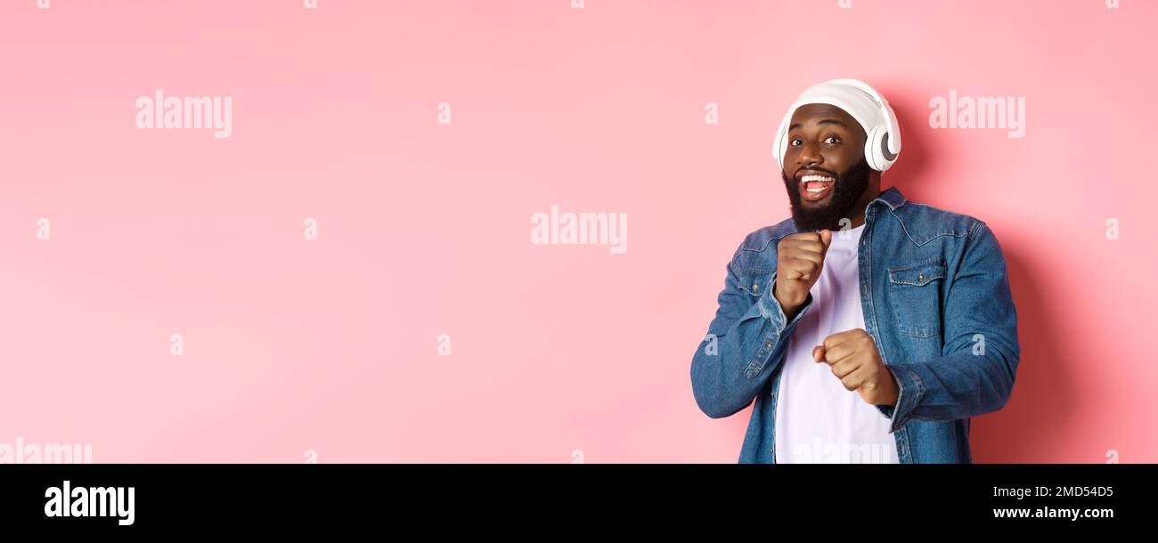 Happy african-american man dancing, listening music in headphones and ...