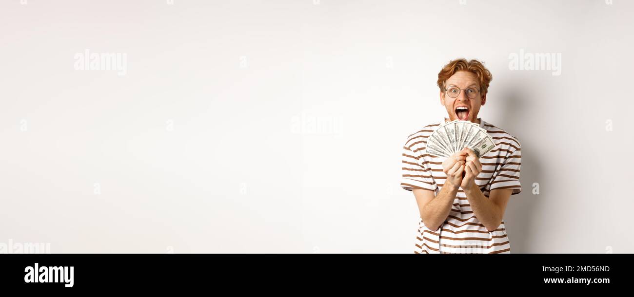 Lucky young man with red hair showing dollars, winning money and ...
