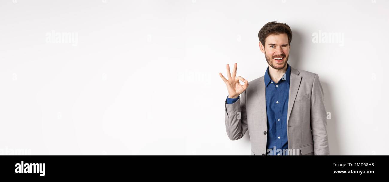 Everything okay. Cheerful businessman in suit winking and showing OK ...