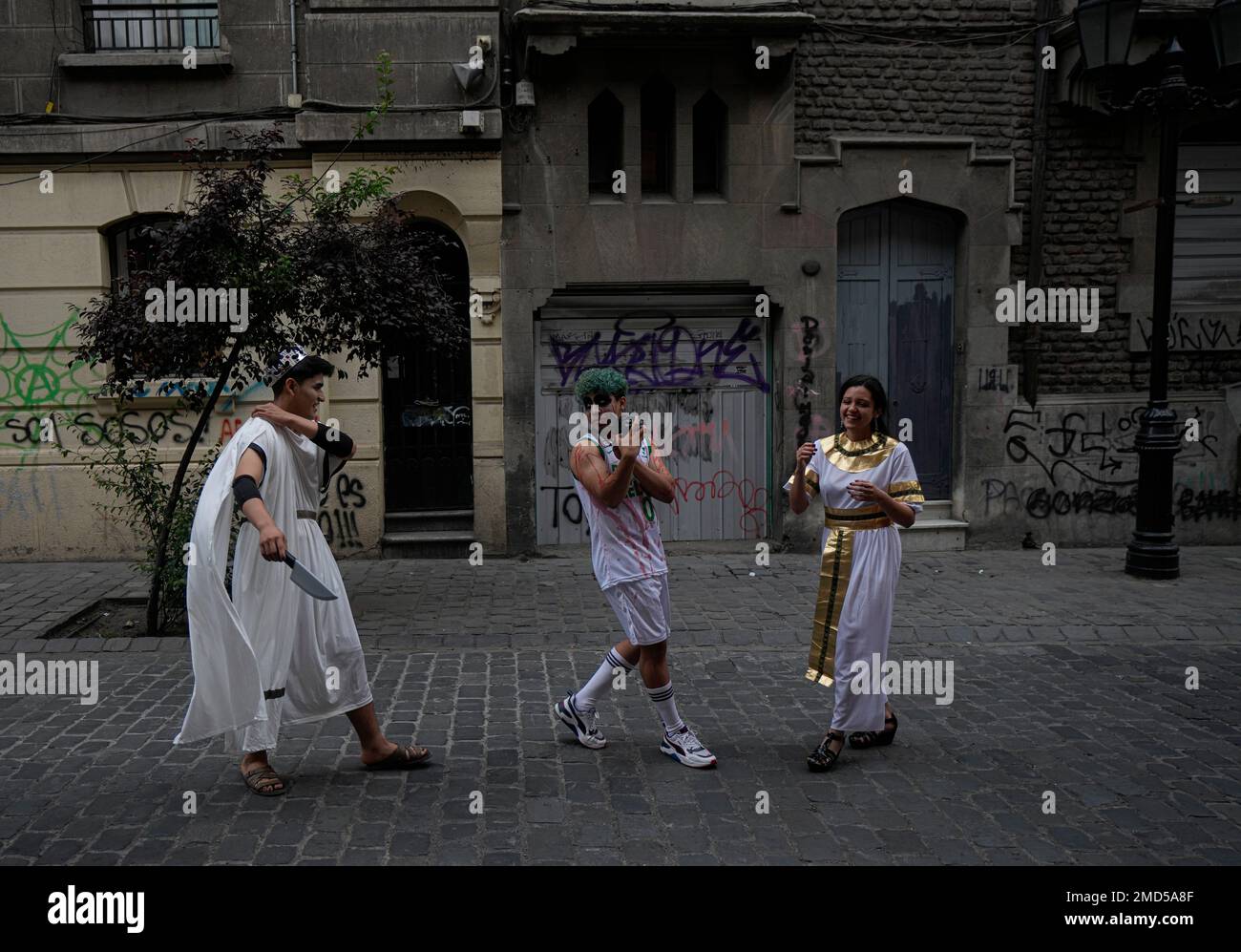 Youths in Halloween costume joke while taking photos on a street in ...