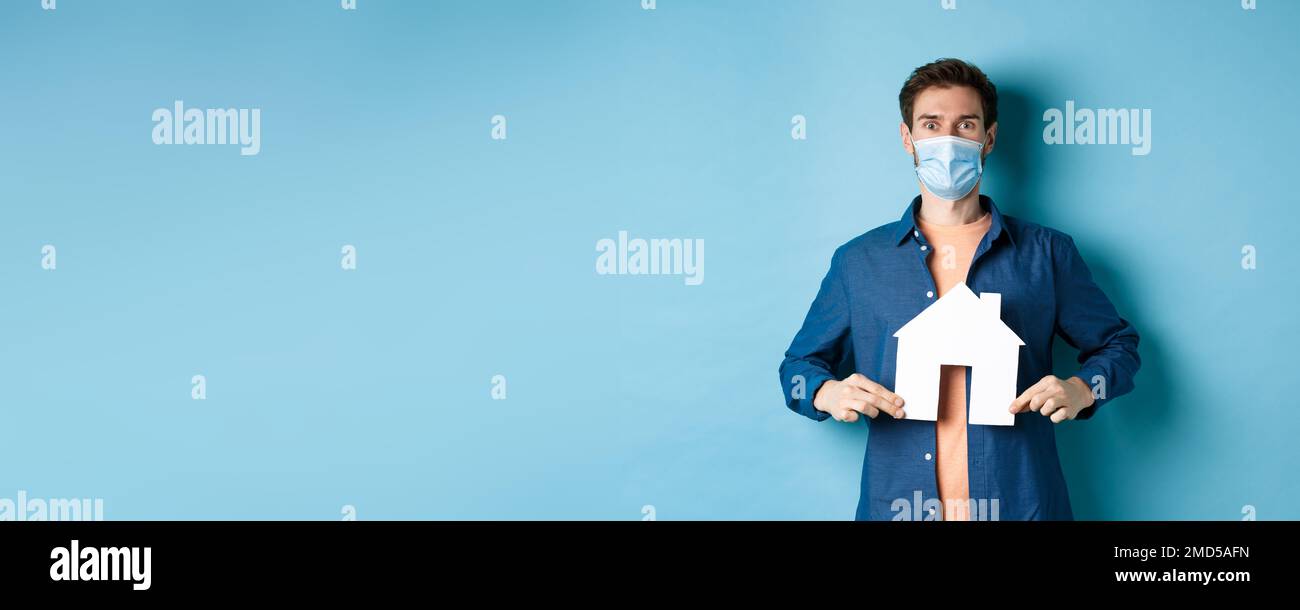 Real estate and covid concept. Happy young man in face mask demonstrate ...