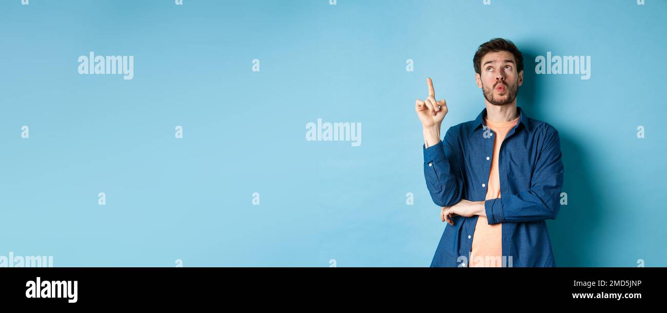 Image of handsome man pitching an idea, raising finger and looking up ...