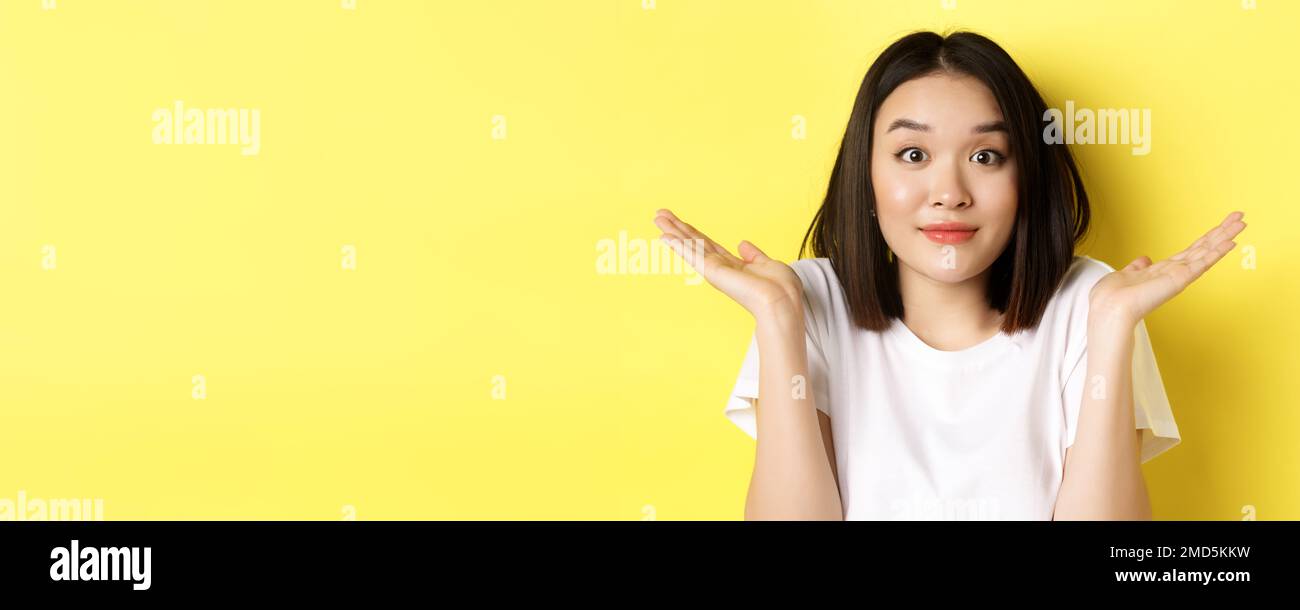 Silly mistake. Close up of cute asian girl saying sorry, shrugging ...