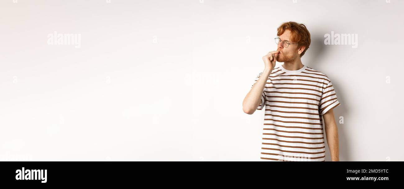 Image of satisfied young man with red hair and glasses kissing fingers ...