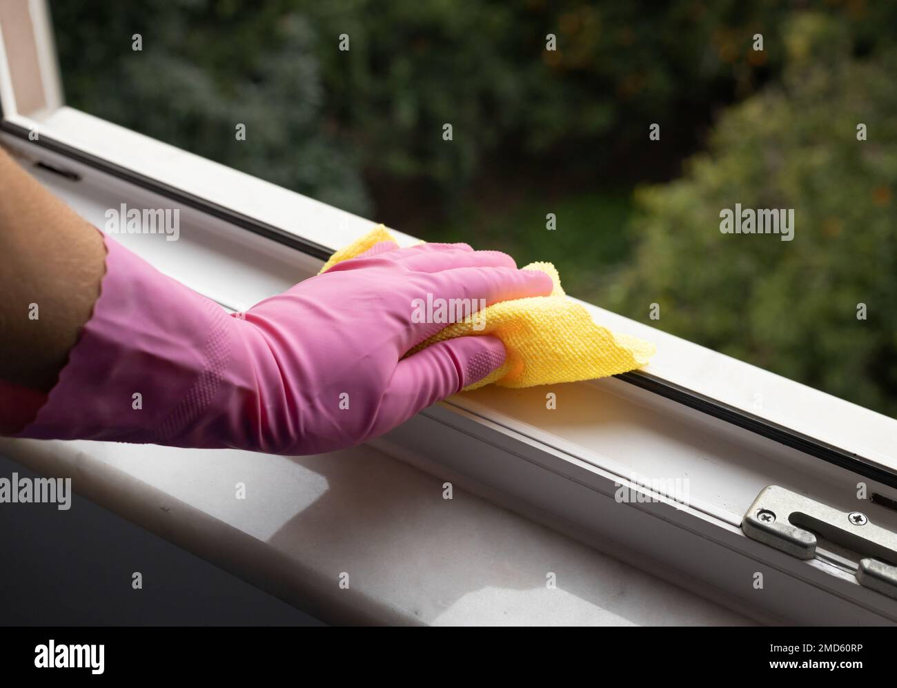 Hand holding a yellow microfiber cloth to clean dust on a window rail ...