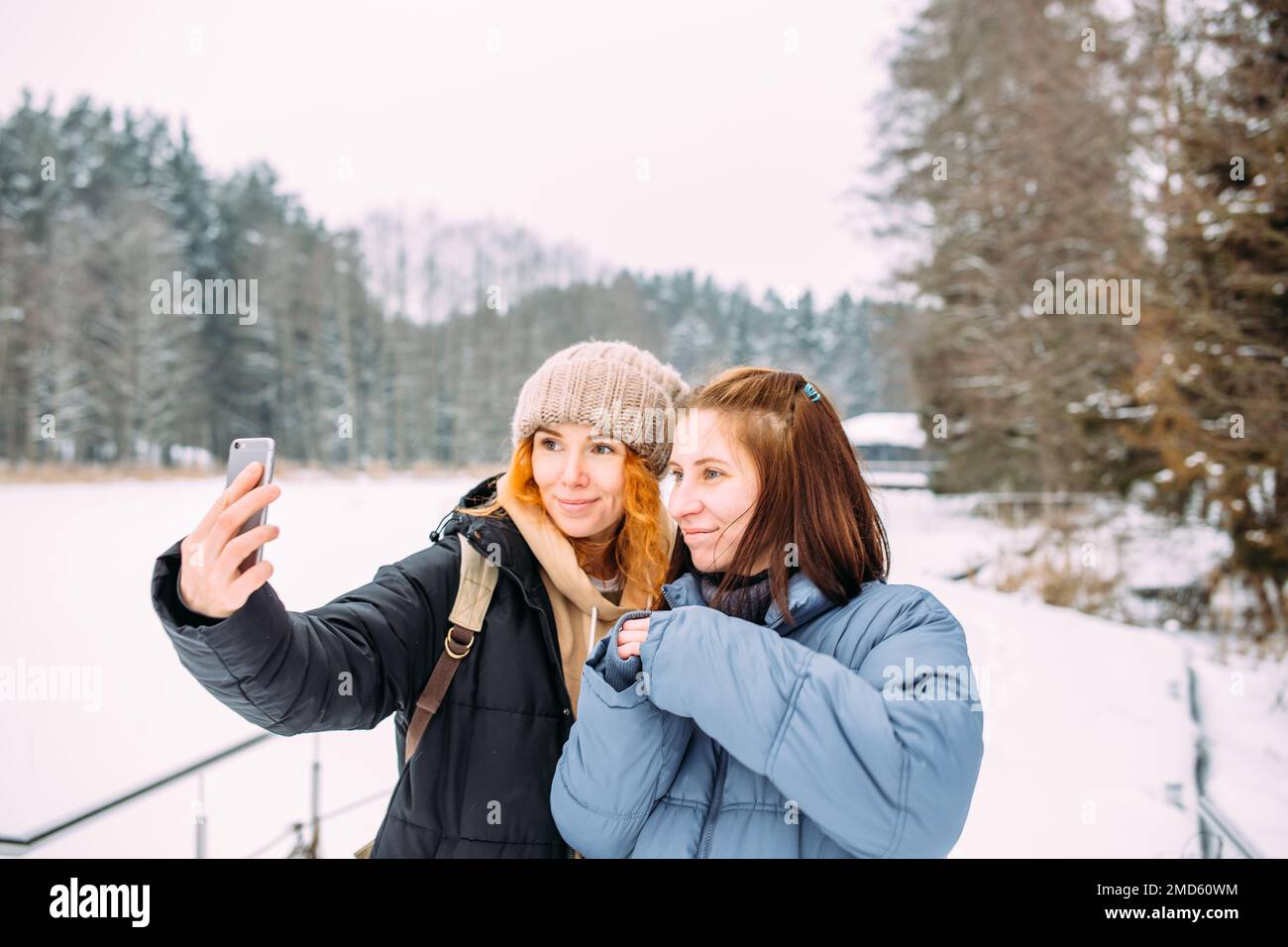 Two women friends in winter with a phone takes a selfie in winter Stock ...