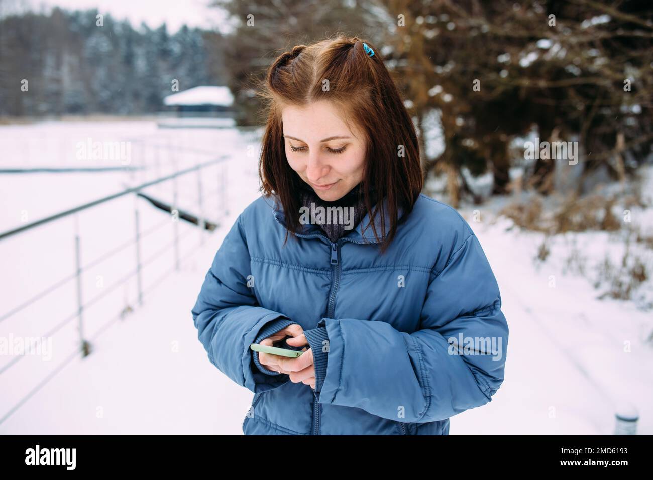 beautiful woman calmly waiting, talking on the phone in a snowy ...