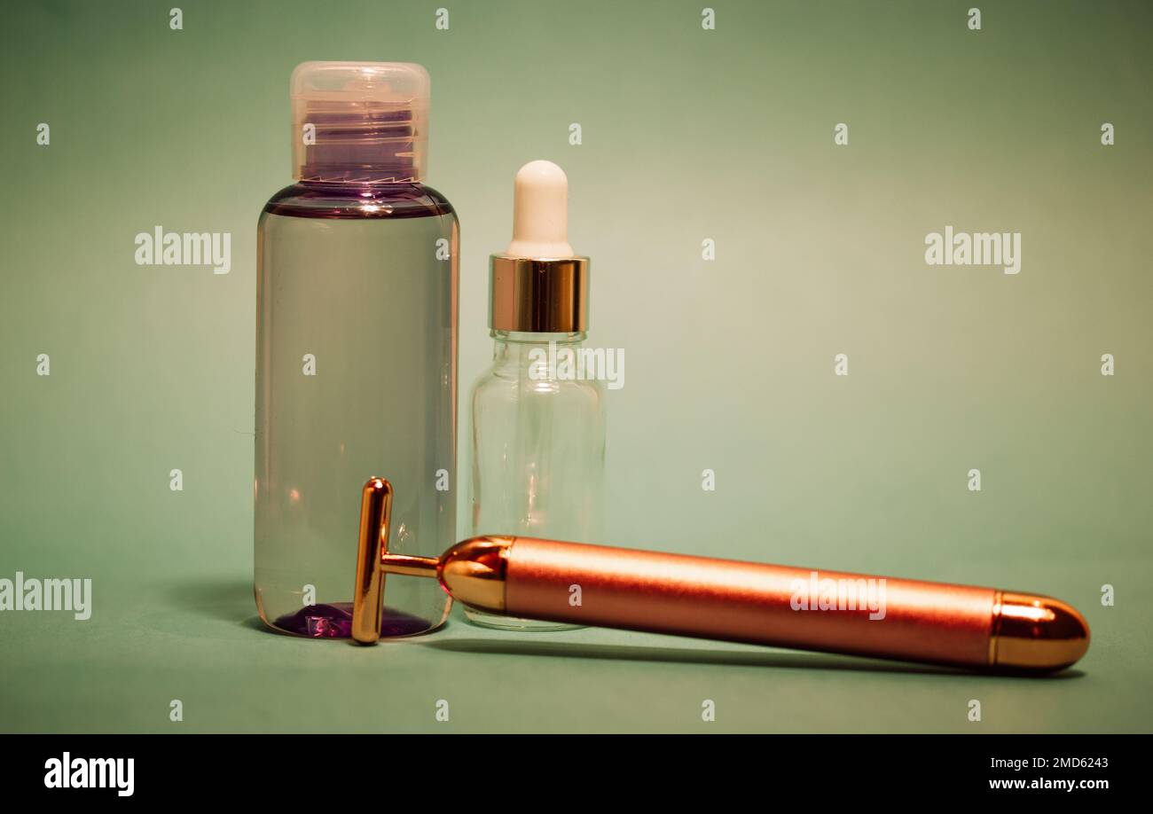 Vibrating golden facial massager, glass jar with oil dropper for ...