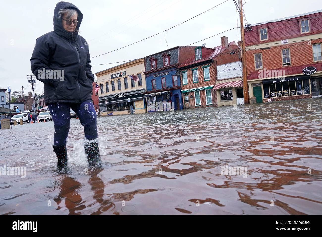 A person walks on a flooded sidewalk in downtown Annapolis, Md., Friday ...