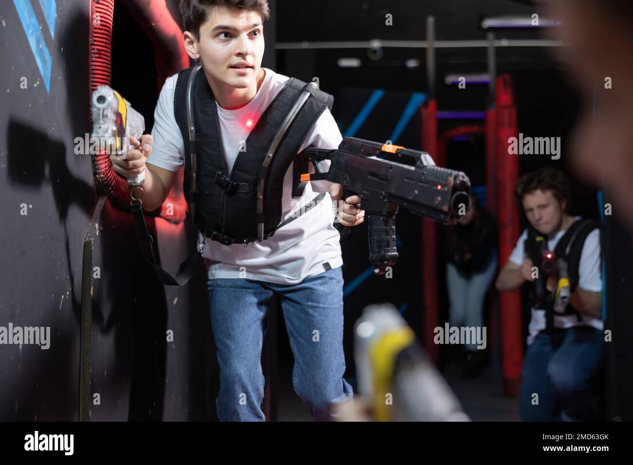 Emotional man with laser pistol playing laser tag with friends on dark ...