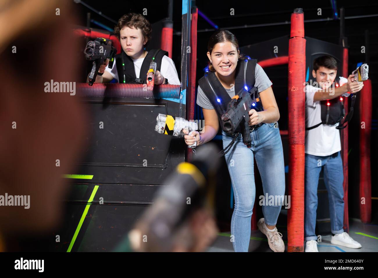 Laser tag players young mens and womens playing in teams in dark laser ...