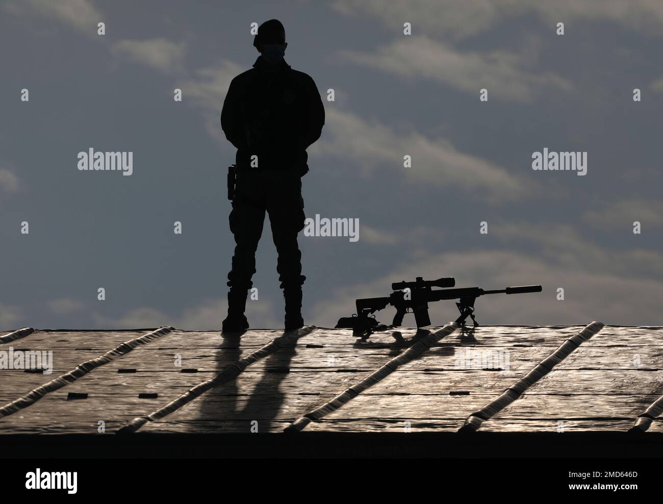 A Presidential security officer stands on the roof of a building as ...