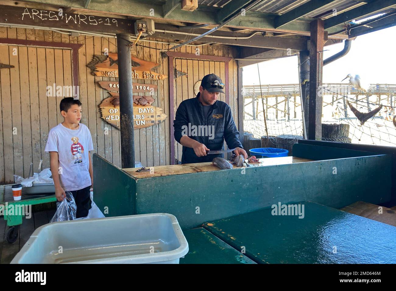 Scott Breneman, owner of West Caught Fish, slices fish for a customer ...