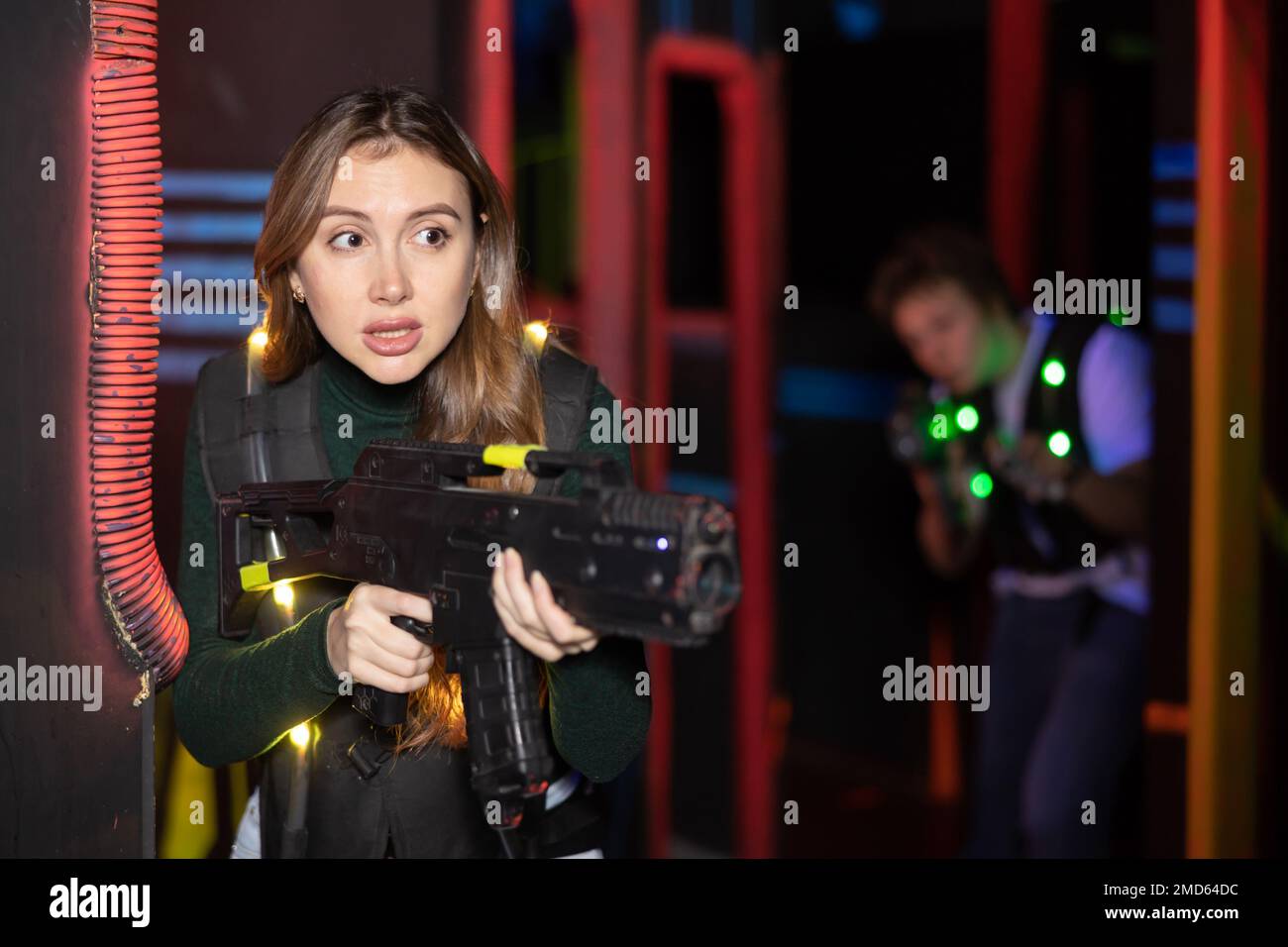 Smiling girl with laser pistol during playing laser tag with her ...