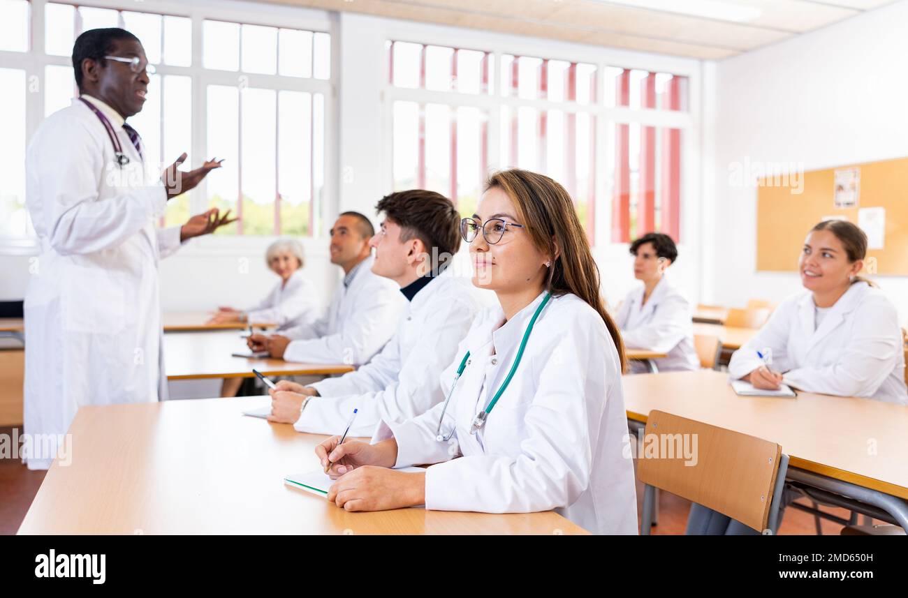 Young hispanic female medical student taking notes during group lecture ...