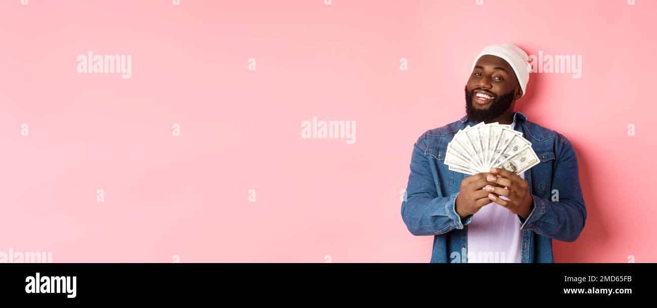 Satisfied rich african-american man showing money, smiling pleased and ...
