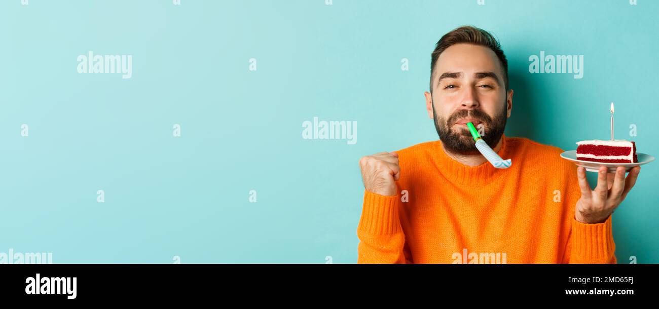 Close-up of funny adult man celebrating his birthday, holding bday cake ...