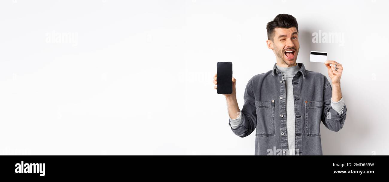 Cheerful handsome guy showing good deal, empty smartphone screen and ...