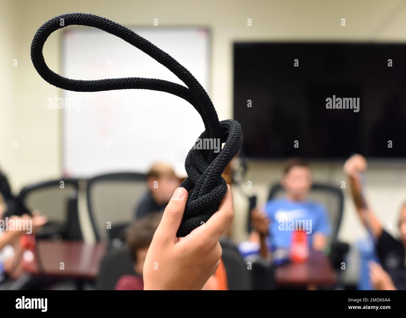 A junior firefighter student holds up a figure-eight knot during class ...