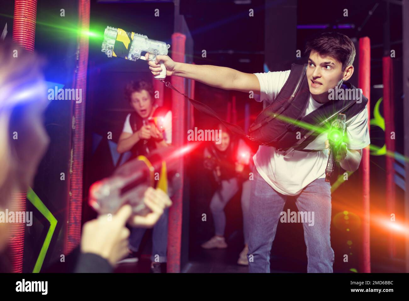 Emotional man with laser pistol playing laser tag with friends on dark ...