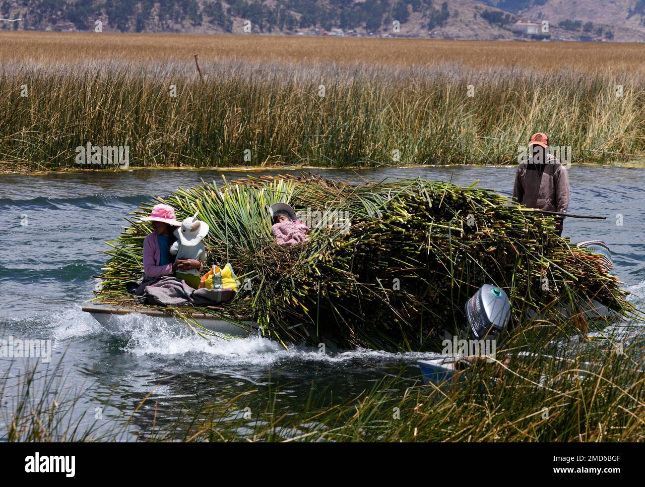 A child sleeps on a bed of feather grass as a family travels on a boat ...