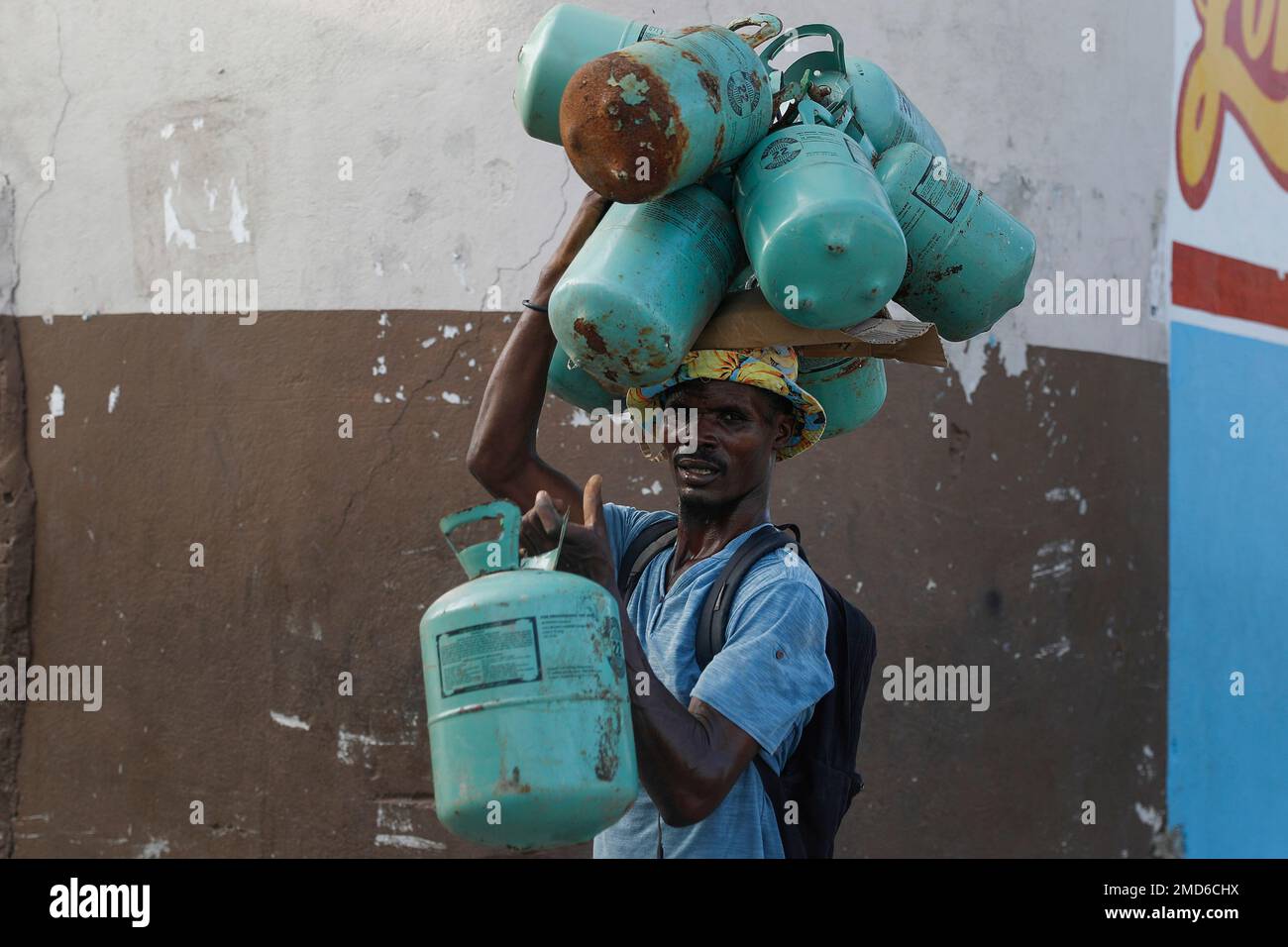 A man walks past balancing empty gas canisters on his head, in Port-au ...