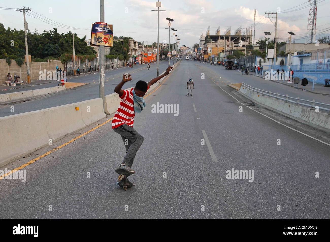 A youth rides his skateboard on a road free of traffic, in Port-au ...