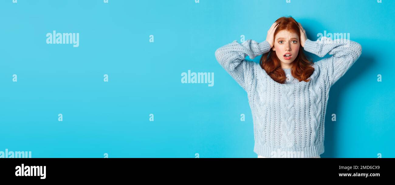 Nervous redhead girl standing overwhelmed, holding hands on head in ...