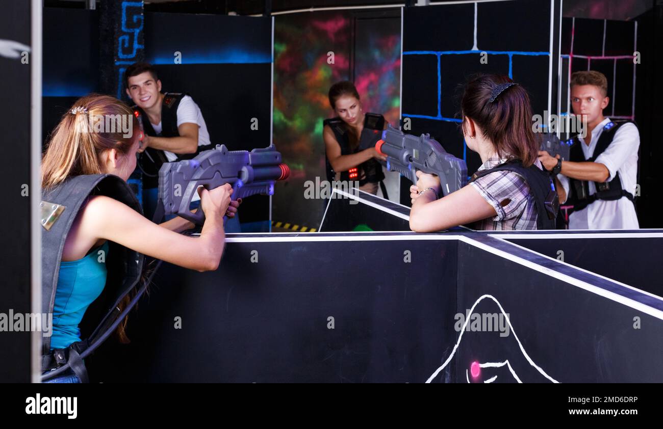 Excited people playing enthusiastically laser tag game Stock Photo - Alamy