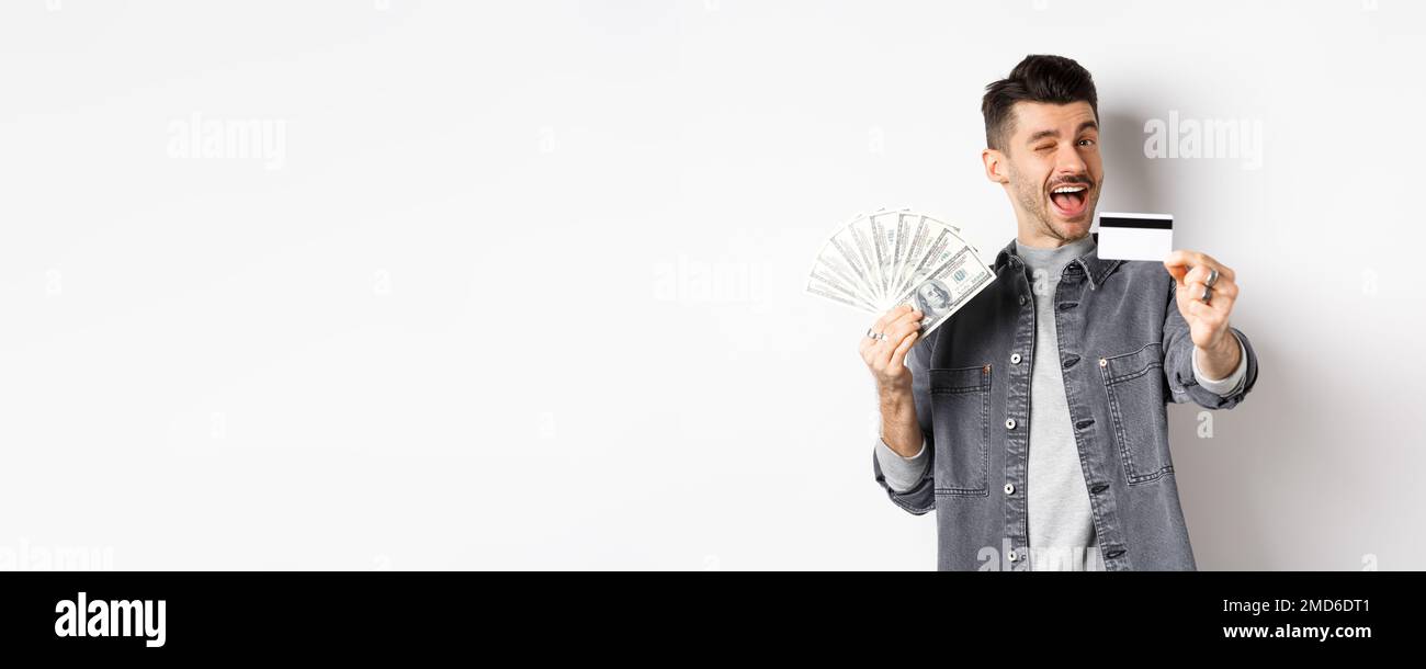 Image of handsome guy holding dollar bills but suggesting use plastic ...